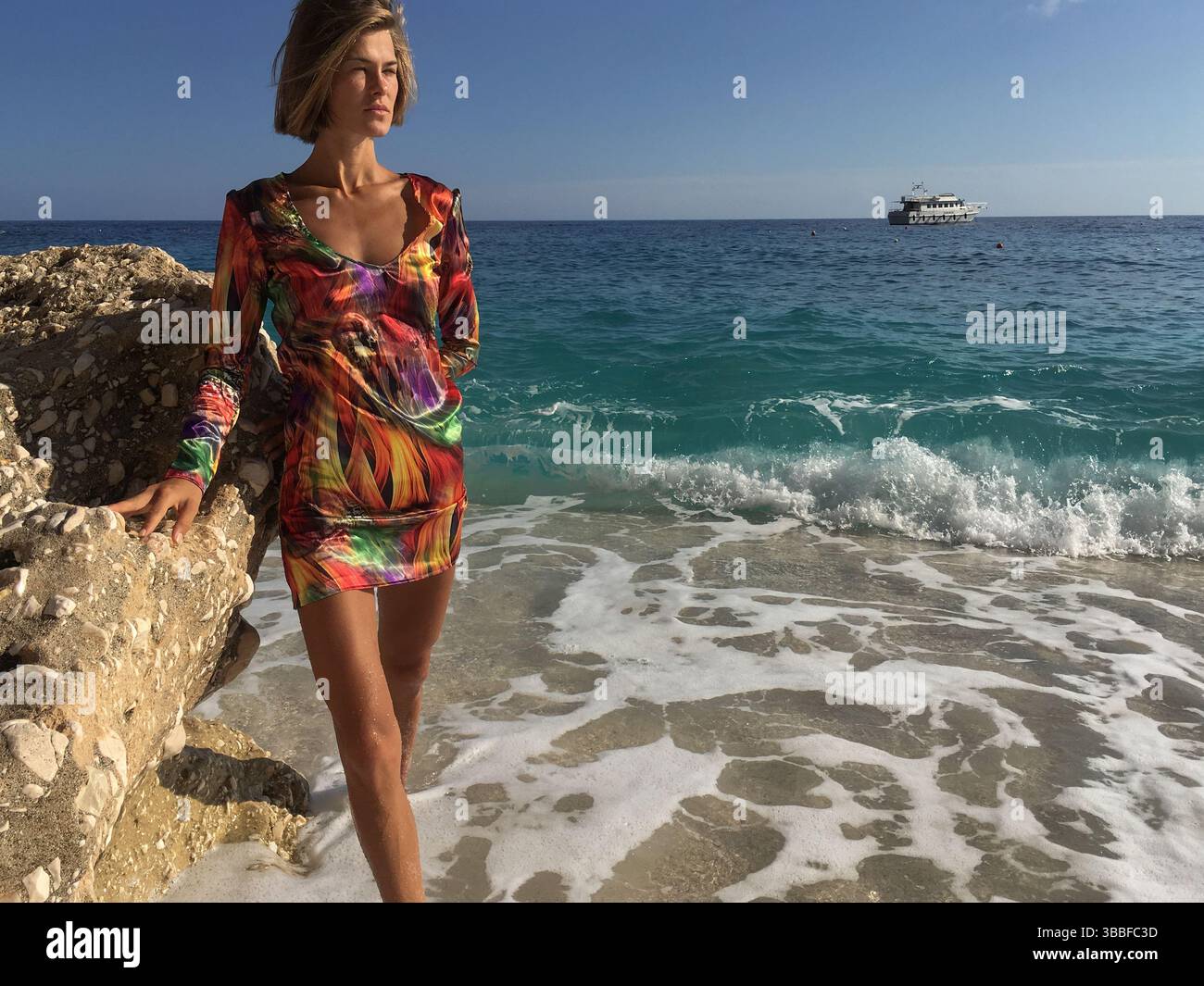 Fashion female model standing next to rock on the beach Cala Mariolu ...