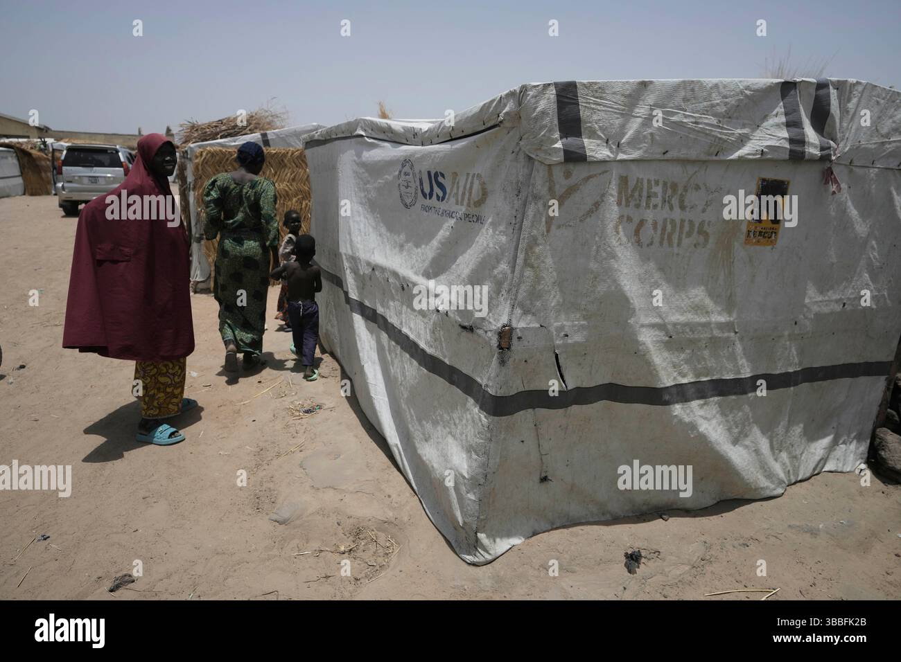 A woman and her child walk past a USAID tent at the internal displaced ...