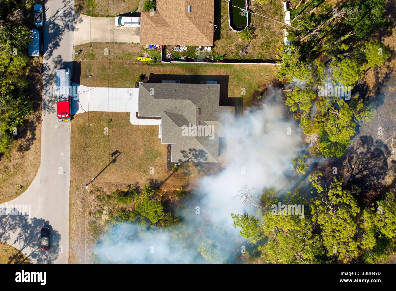 Smoke rises from a vegetation fire near suburban homes in Florida, as firefighters deploy hoses ...