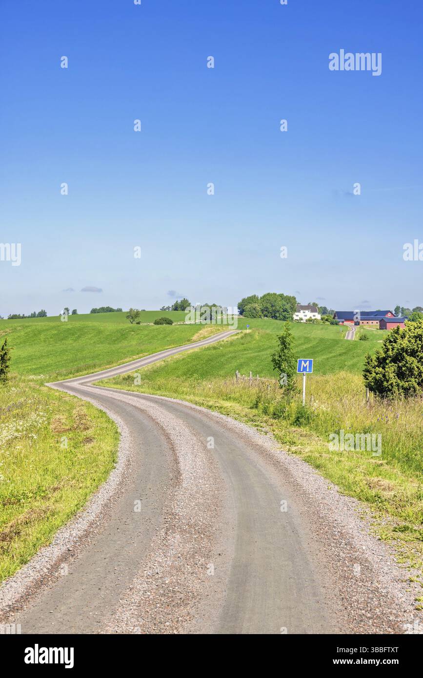 Empty winding gravel road in the countryside with a meeting place sign ...