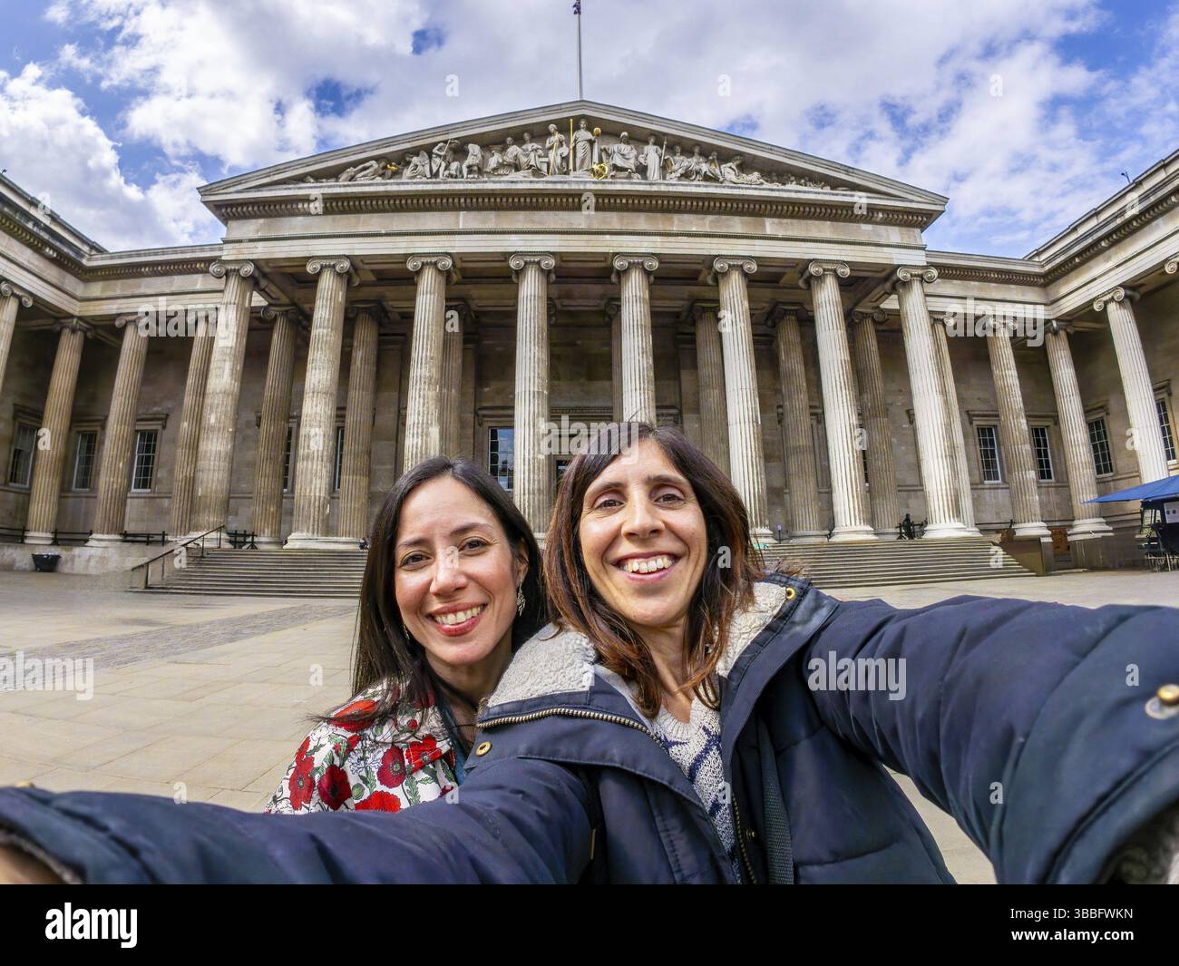 Two happy female tourists are taking a selfie with a fisheye lens in ...