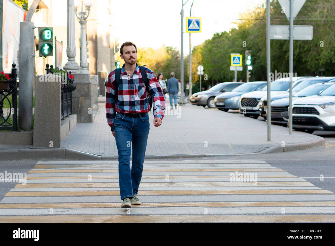Man crossing street at pedestrian crosswalk in city center. Guy with ...