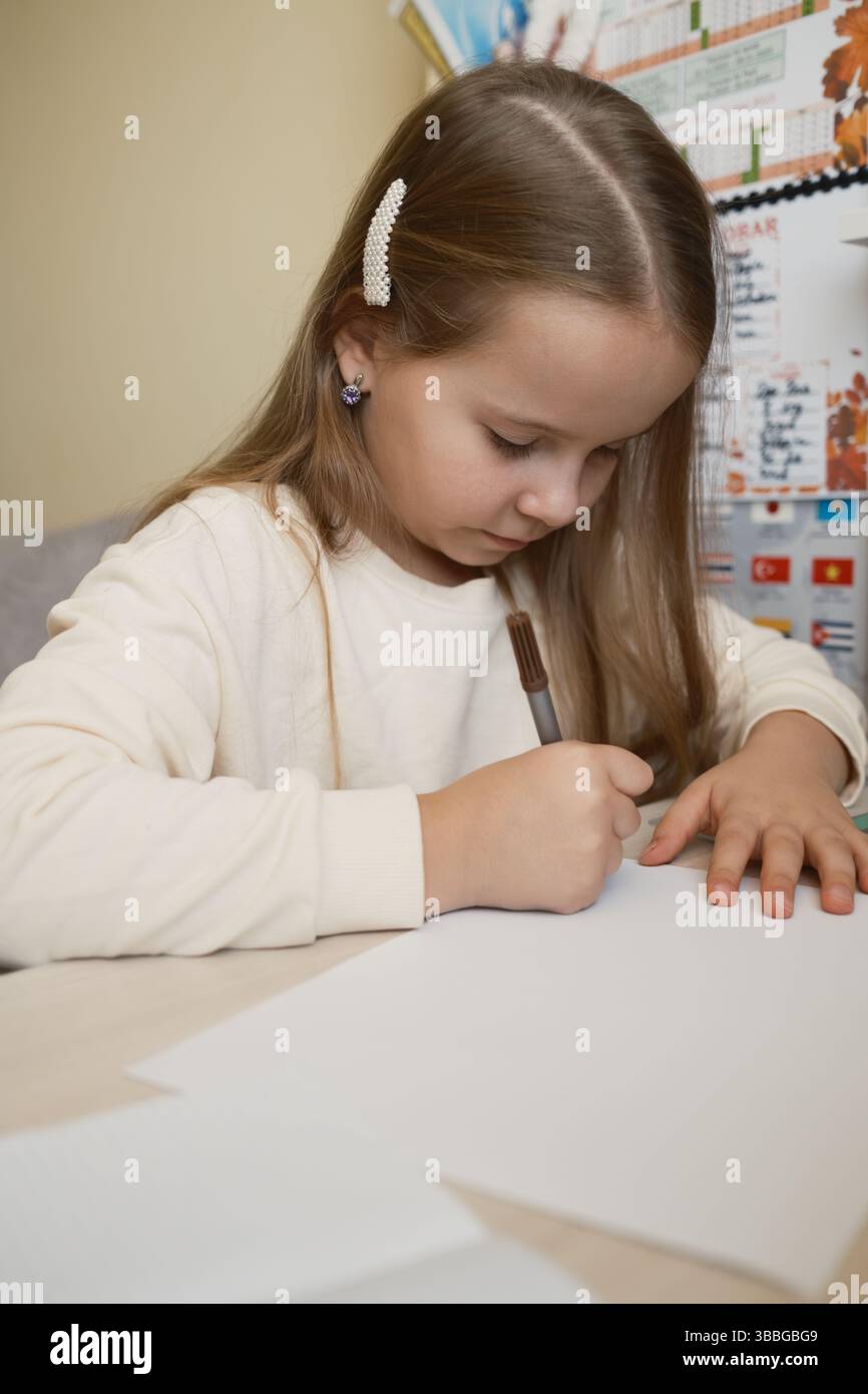 Young girl writing on paper during homework time at a desk Stock Photo ...