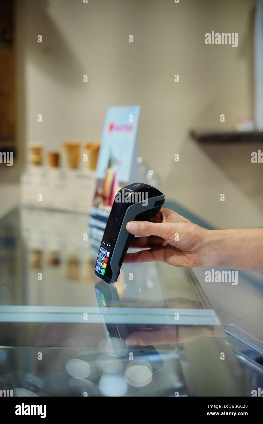 Hand holding a card reader in a store setting, ready for contactless ...