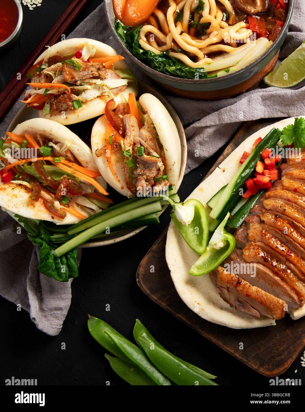 Set of Chinese dishes on dark background: sweet and sour duck, noodles ...
