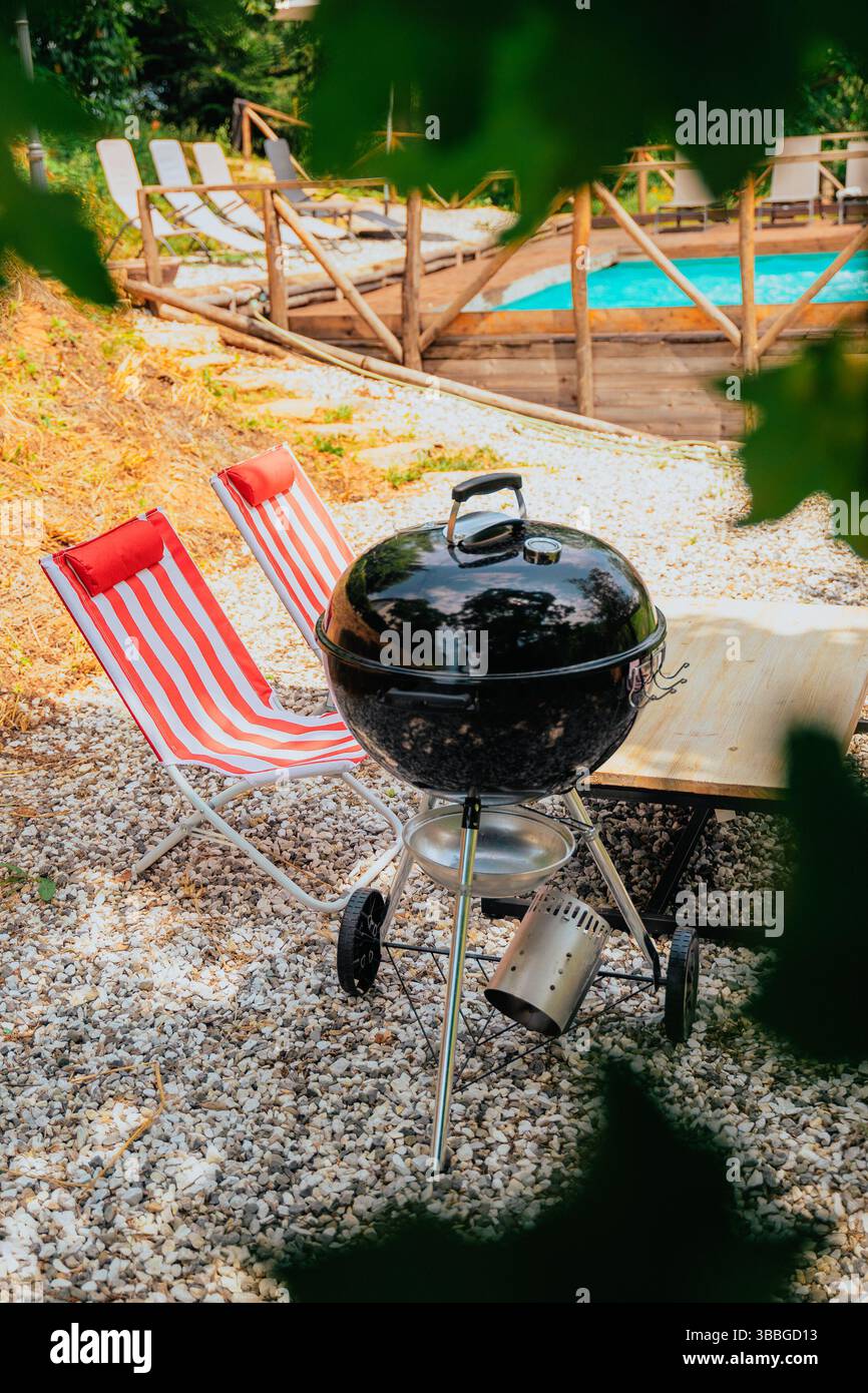 Cozy outdoor barbecue area featuring a charcoal grill and two red ...