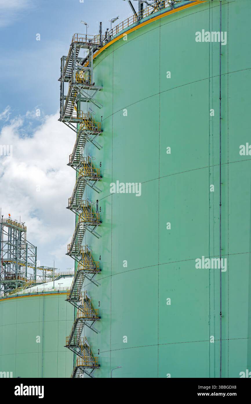 An image of a tall, cylindrical, green industrial storage tank with a ...