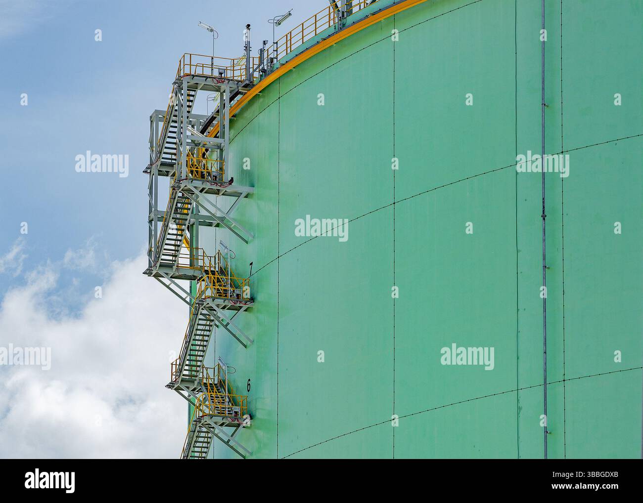 An image of a tall, cylindrical, green industrial storage tank with a ...
