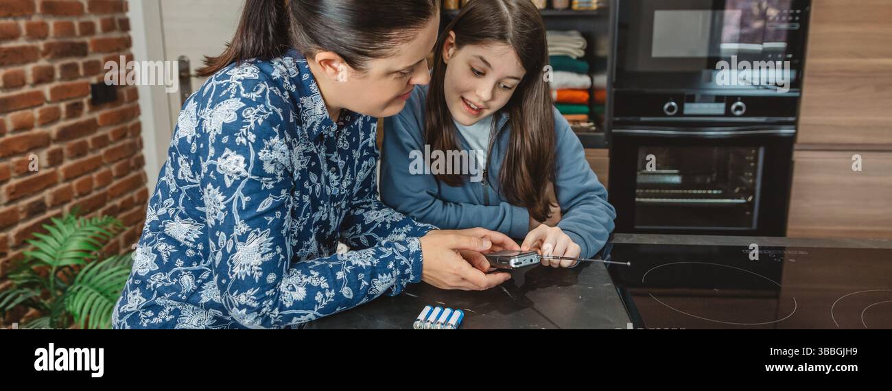 Banner of mother teaching daughter in kitchen how to use analog radio ...