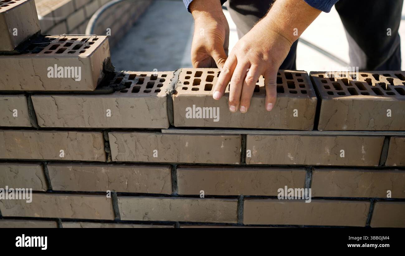 Construction worker carefully placing bricks and applying mortar ...