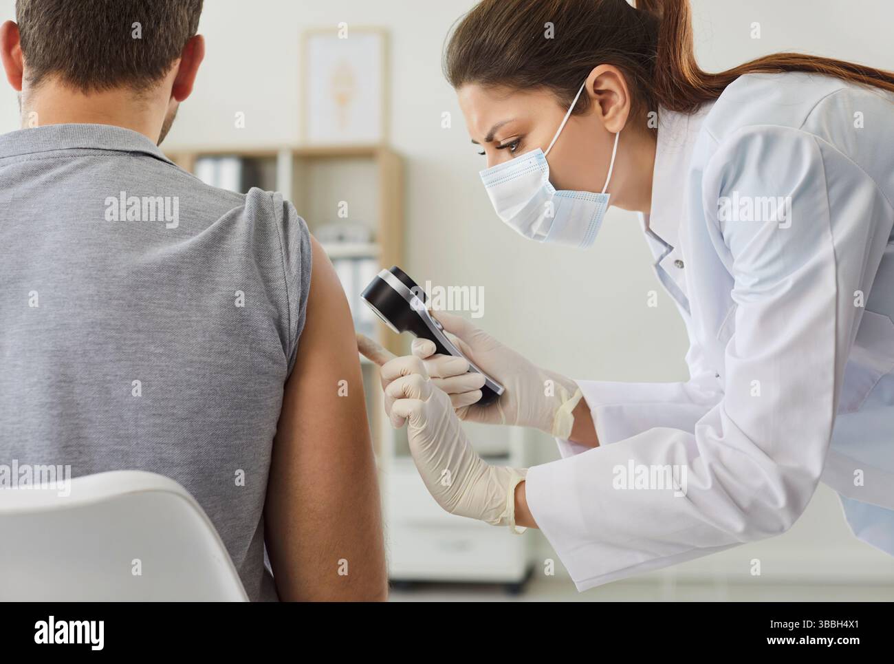 Female doctor examining hand skin of a young man patient using ...