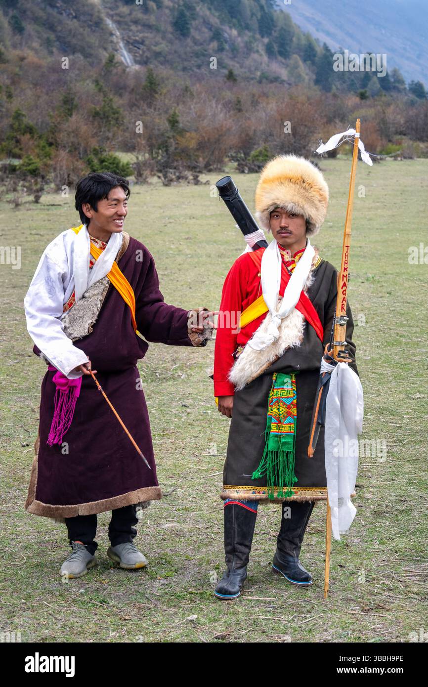 Two young Nubri men in traditional dress prepare for an archery ...