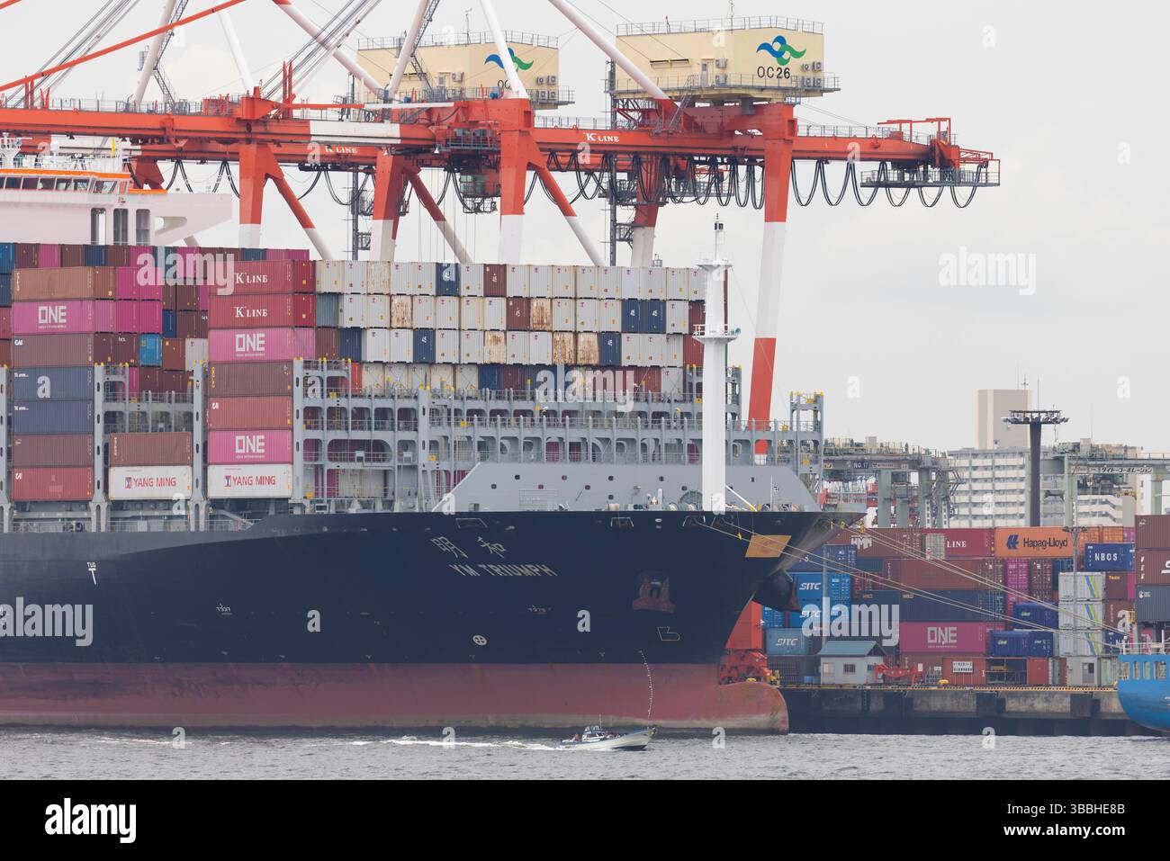 A small boat drives by a loaded container ship inside Tokyo Harbor ...