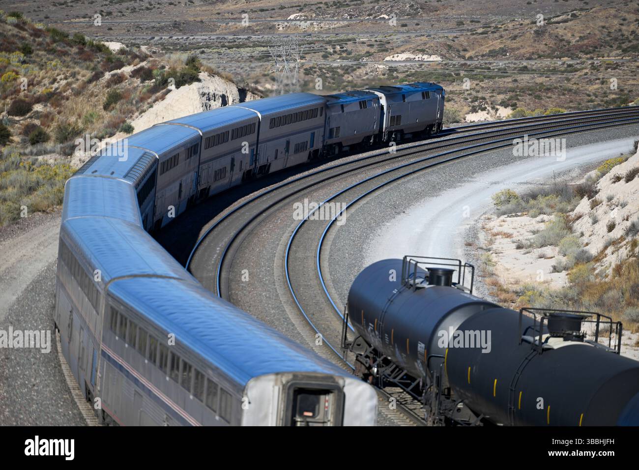 Passenger rail train passing black railroad tank cars Stock Photo - Alamy