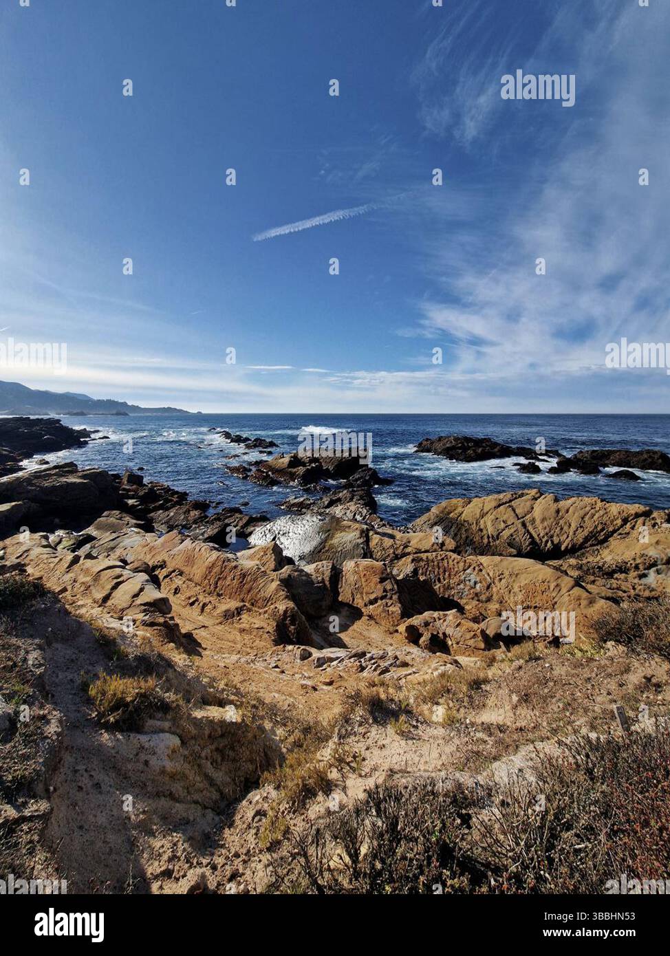 Coastal view with rocky shoreline and ocean waves during a clear day ...