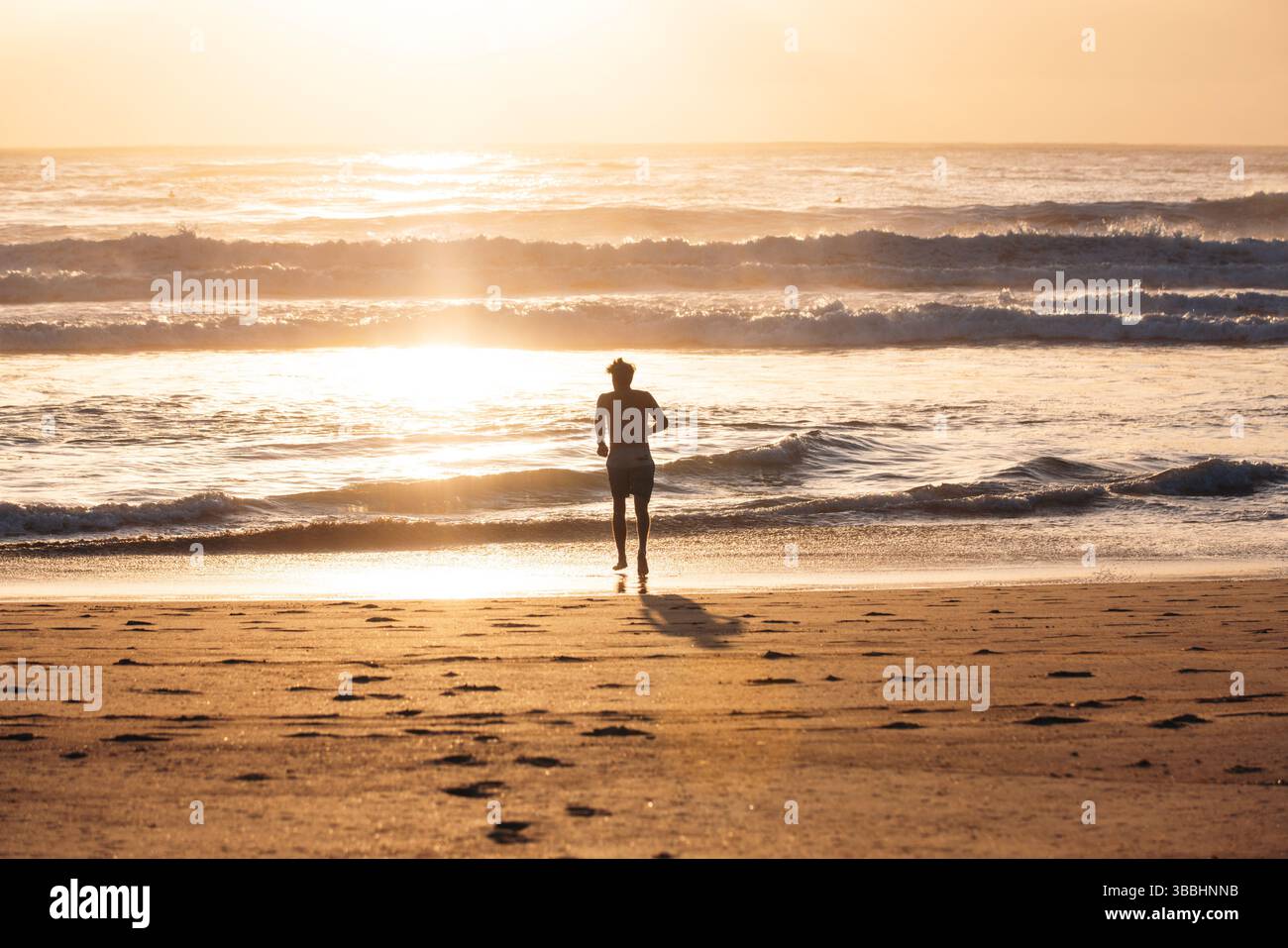 Man running toward the ocean for a swim at sunrise on Manly Beach Stock ...