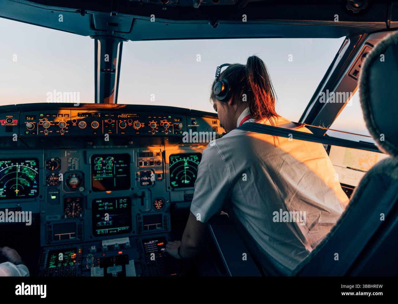 Female pilot in airplane cockpit during golden hour flight Stock Photo ...