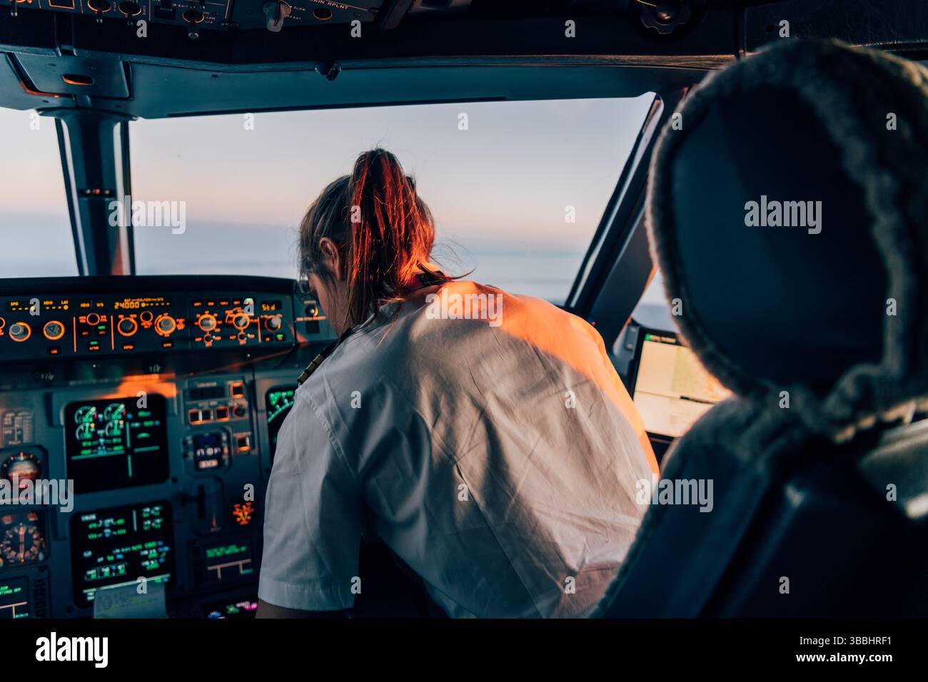 Female pilot operating aircraft cockpit during sunset flight Stock ...