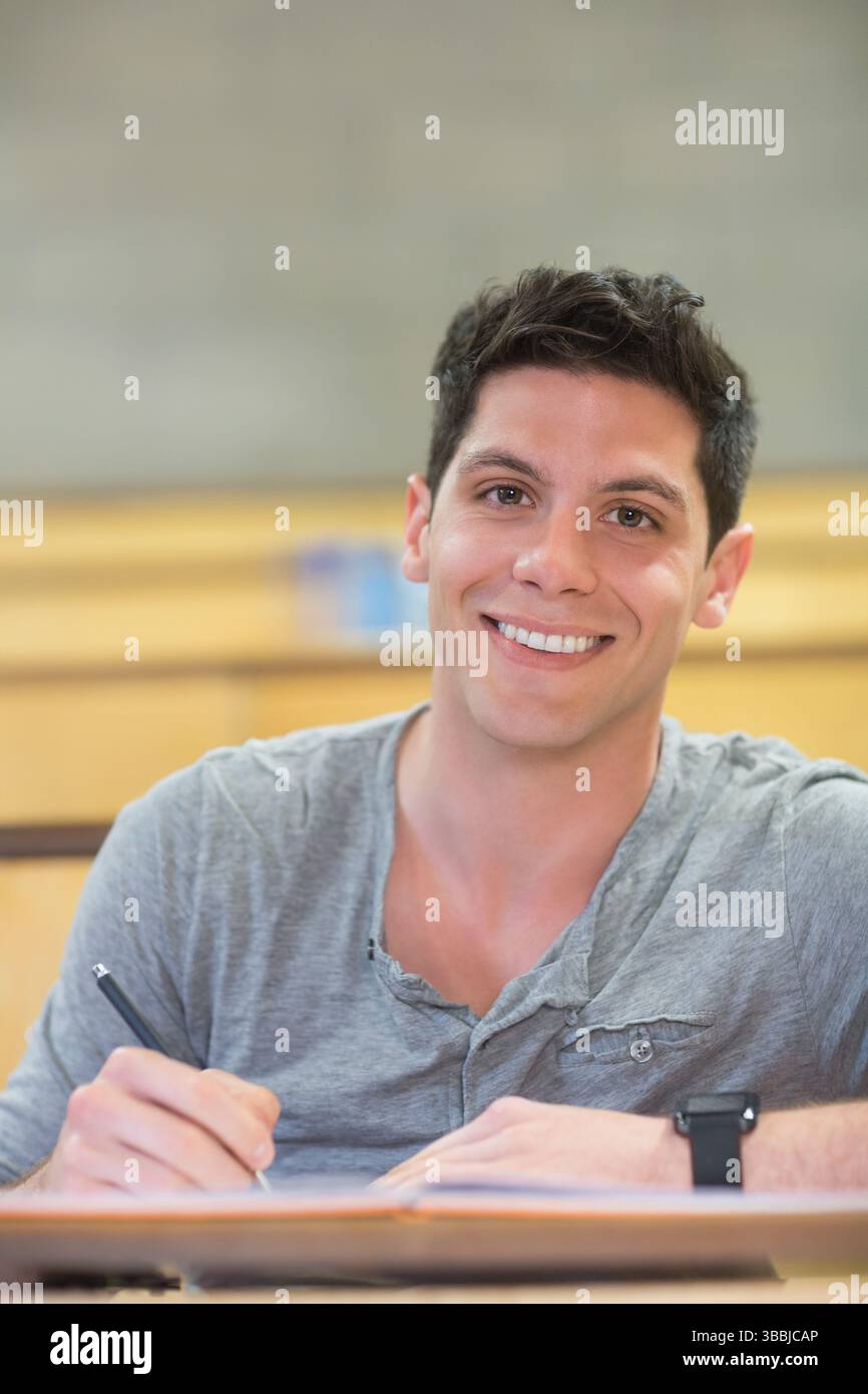 Writing male student taking notes in notebook at university lecture ...