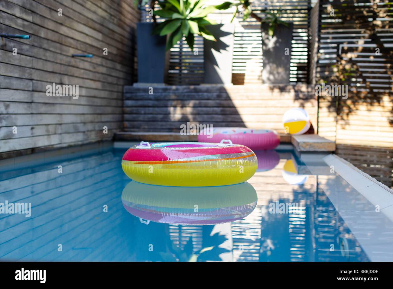 Yellow and pink inflatable ring floating in backyard pool with donut ...
