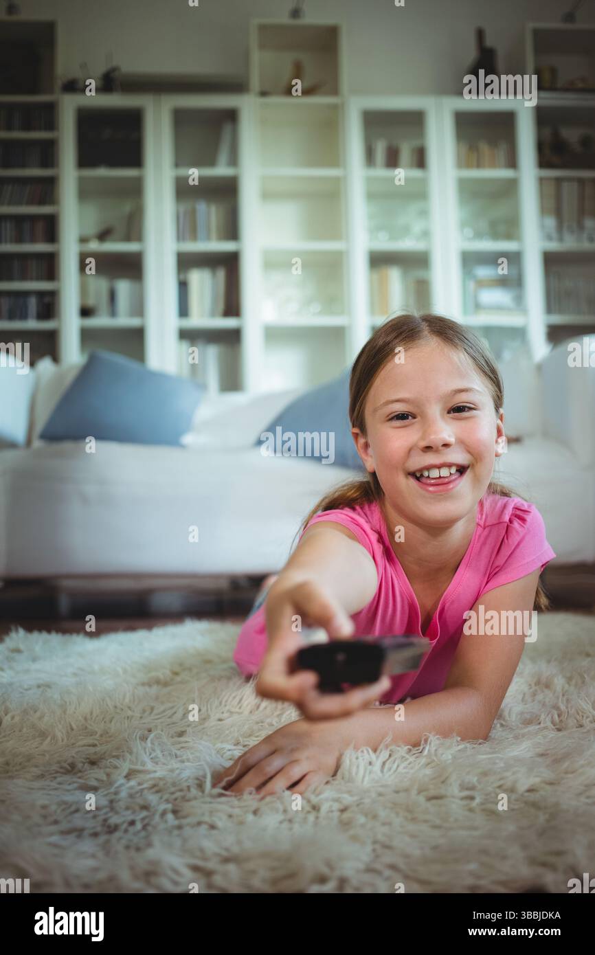 Smiling girl lying on white shag rug near sofa in living room, holding ...