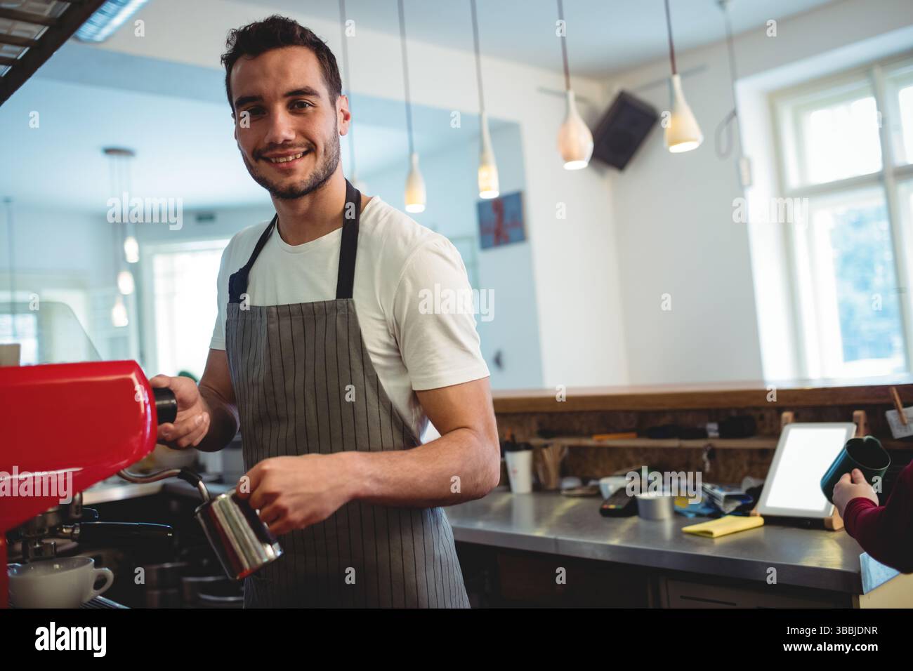 Steaming milk male barista at modern coffee shop, with red espresso ...