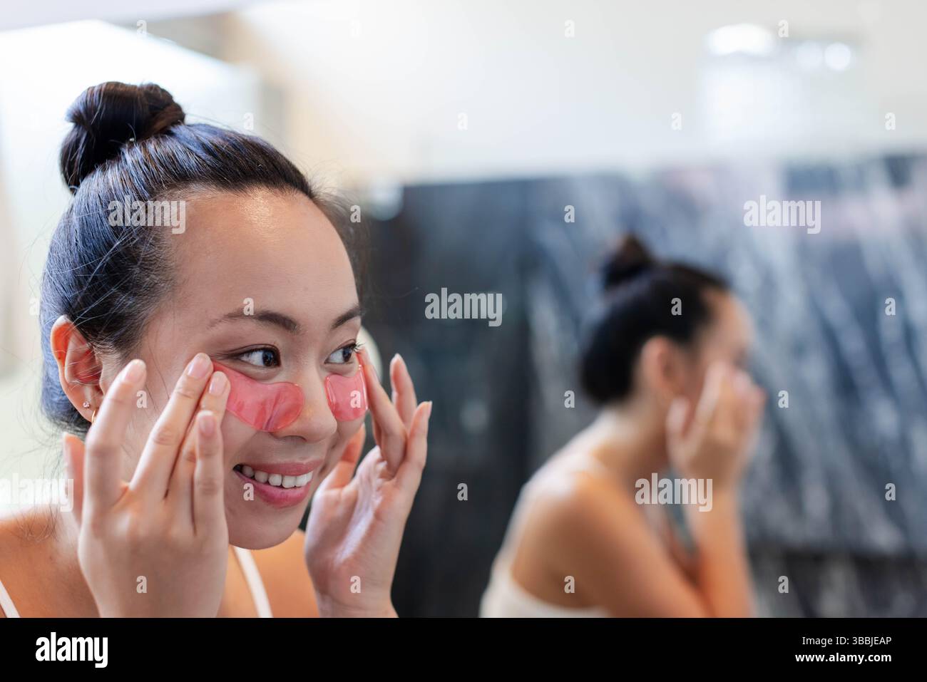Applying Asian woman pressing pink hydrogel under-eye patches at ...