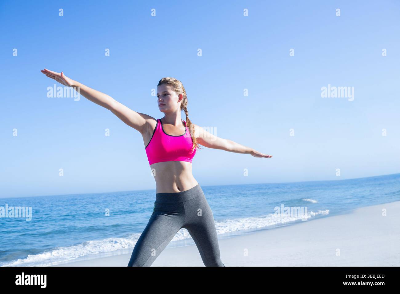 Practicing warrior II pose athletic woman standing on sandy beach, with ...