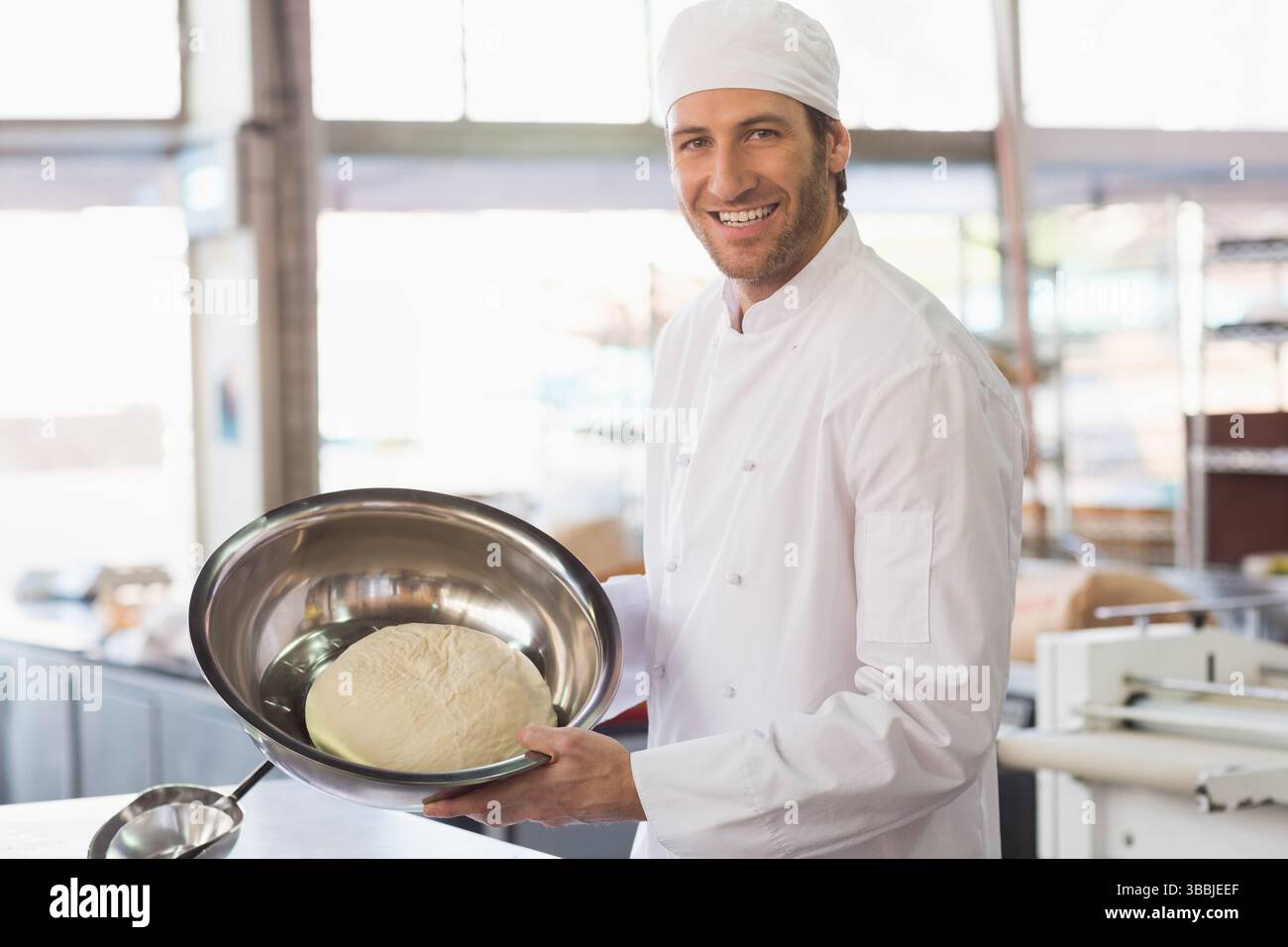 Holding dough in stainless steel bowl, male chef working at counter in ...