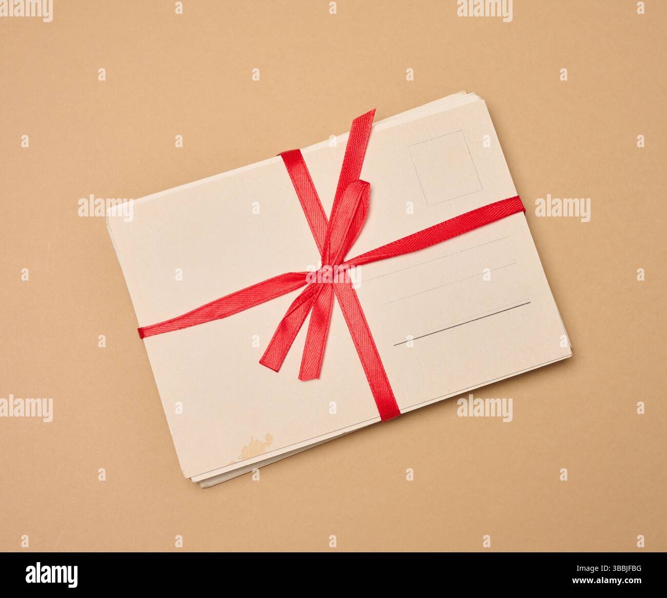 A stack of blank postcards tied with a red ribbon and bow lies on a ...