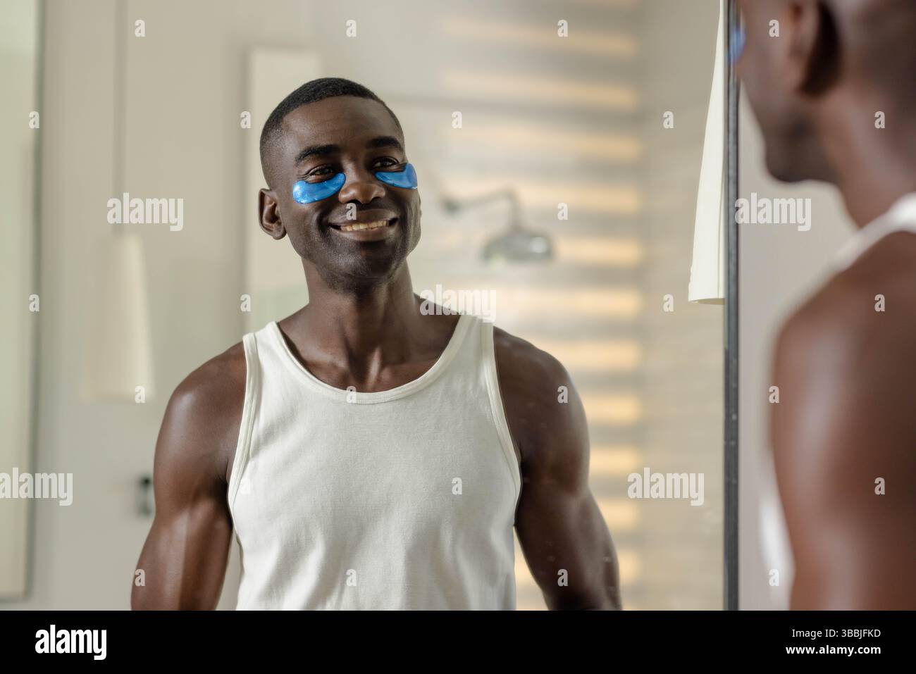 Standing mid adult African American man applying blue under-eye patches ...