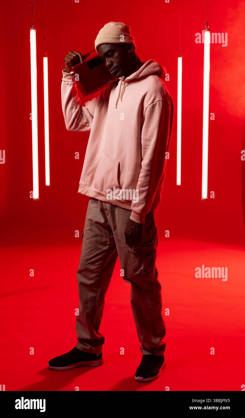 Listening Mid adult African American man holding boombox at ear in red ...