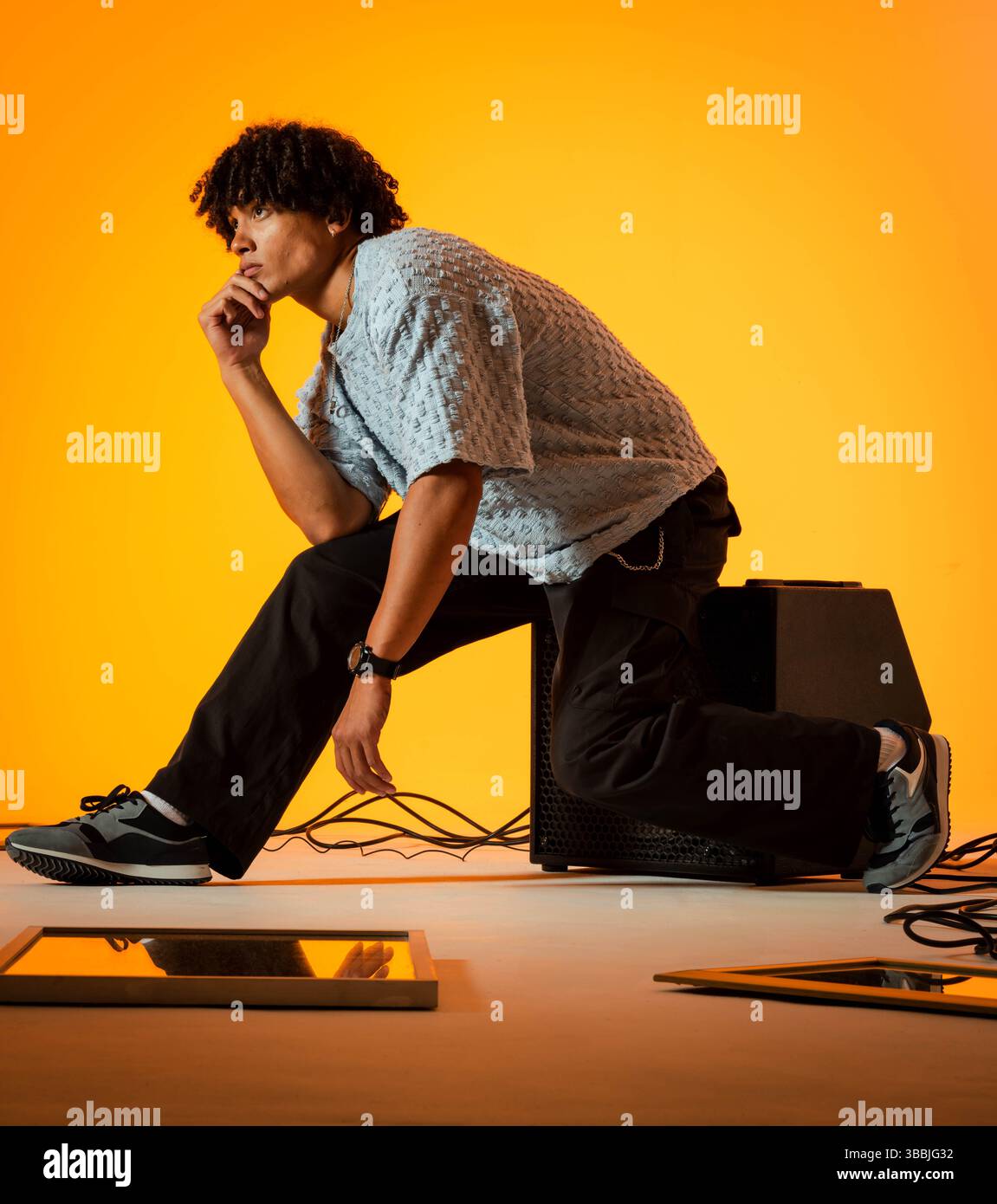Posing African American man kneeling on speaker cabinet in studio, with ...