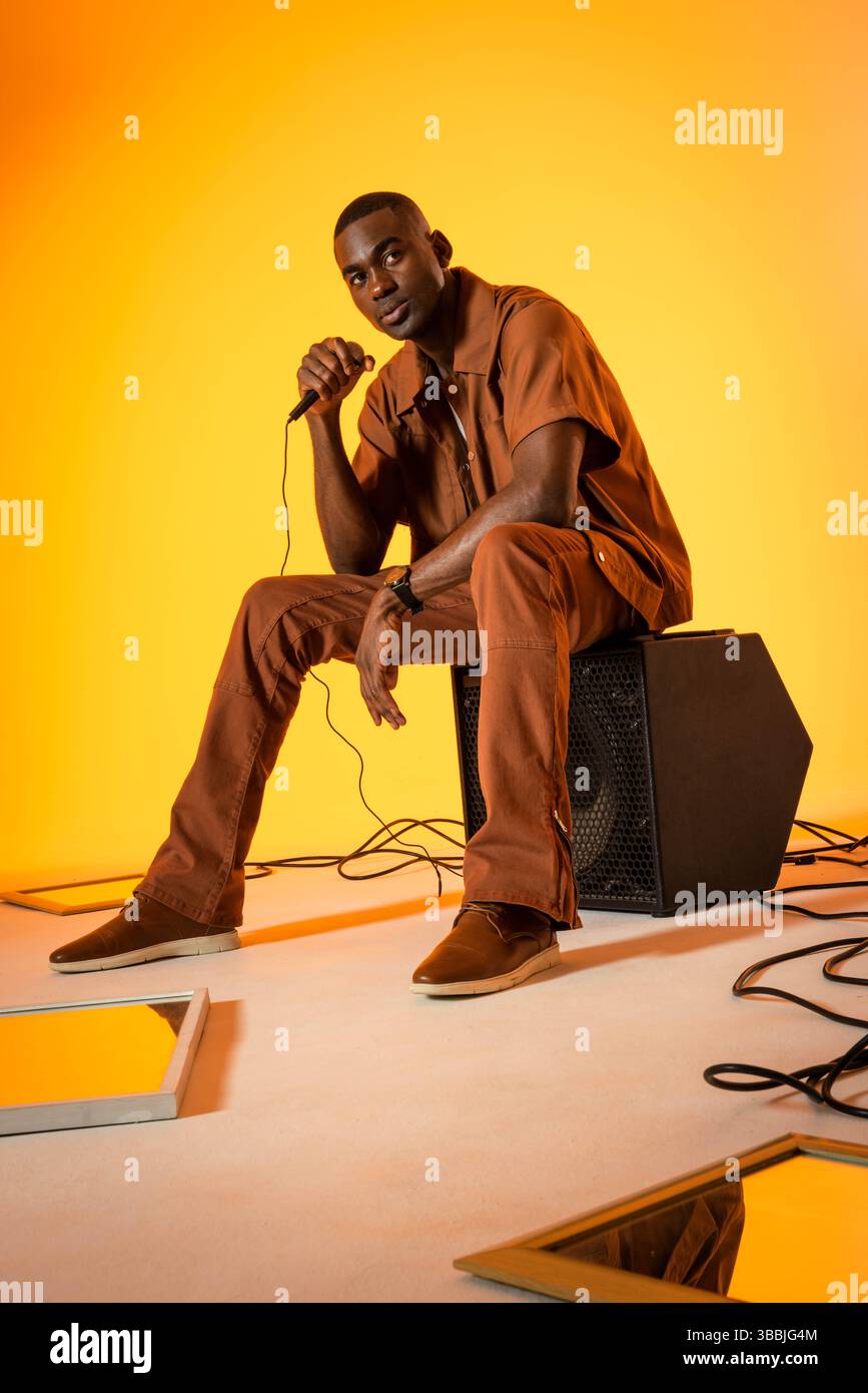 Sitting African American man holding microphone on speaker in studio ...