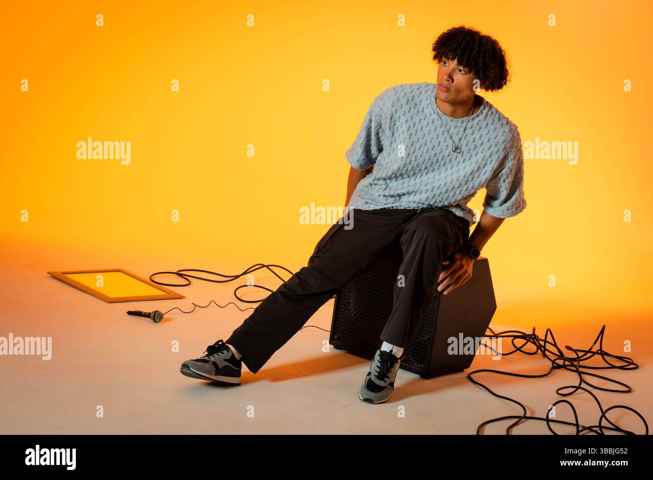 Leaning male sitting on speaker cabinet in studio, with handheld ...