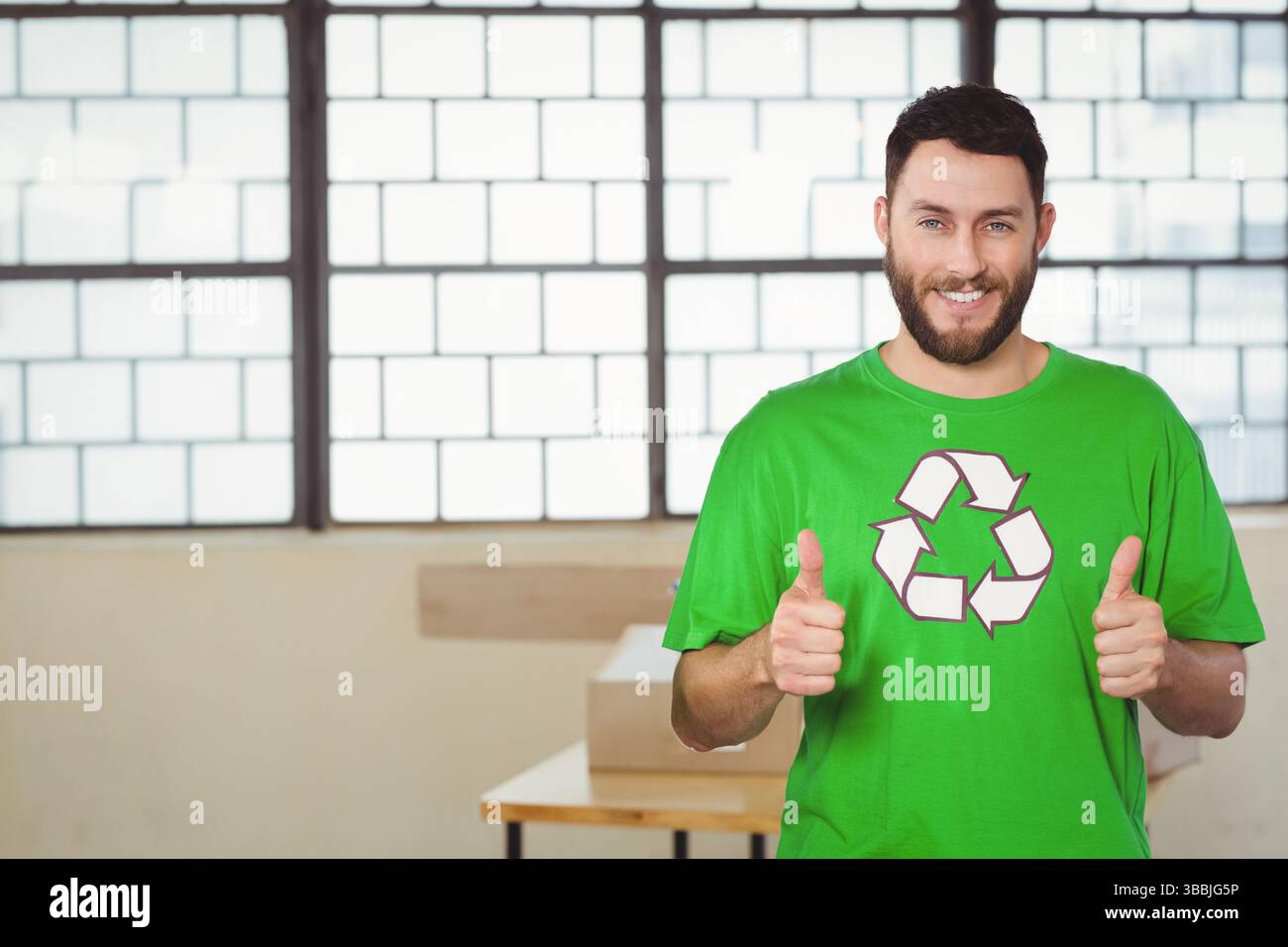 Smiling man wearing green recycling T-shirt giving thumbs up at ...