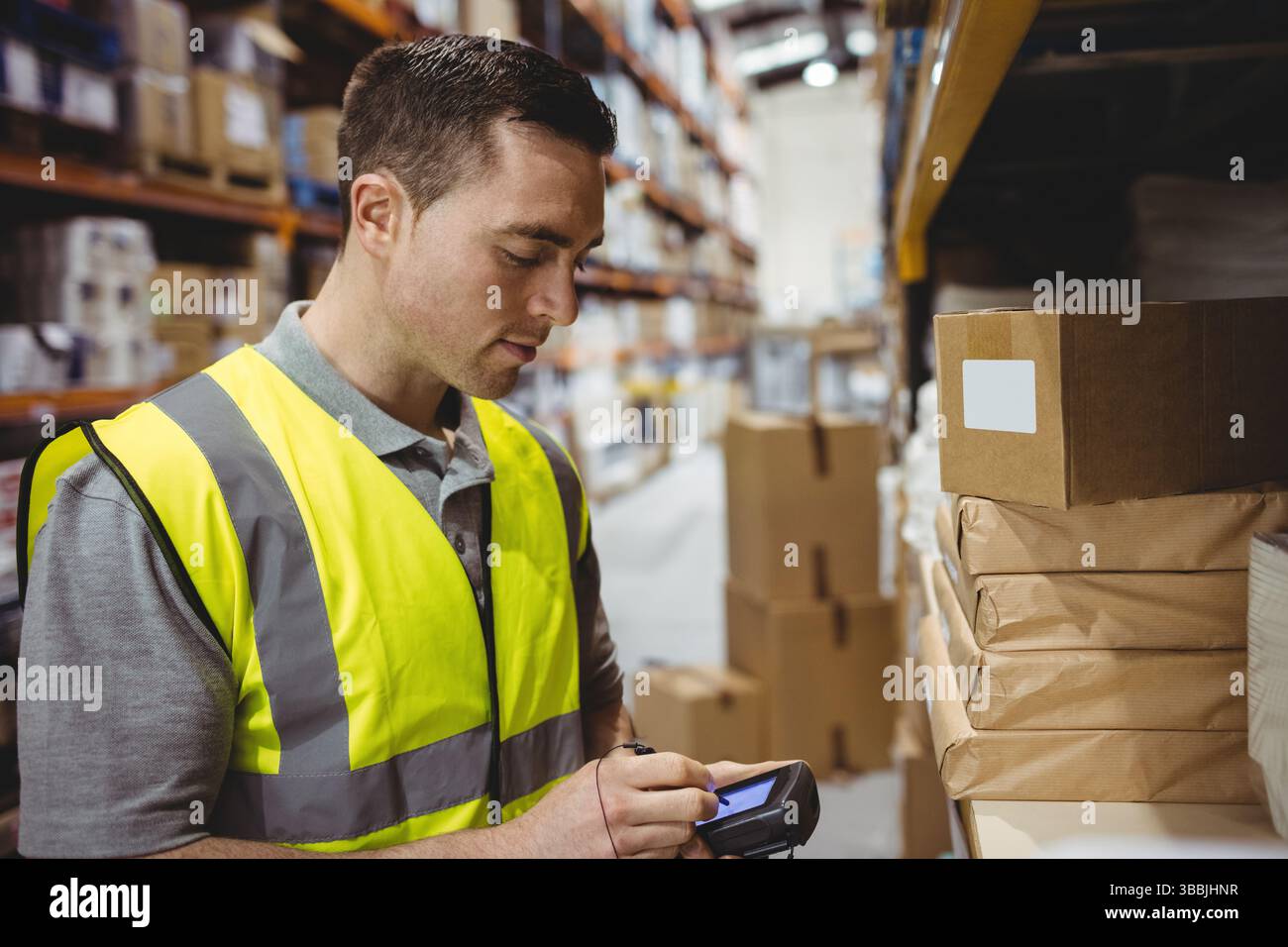 Scanning man using handheld barcode scanner in warehouse aisle, with ...