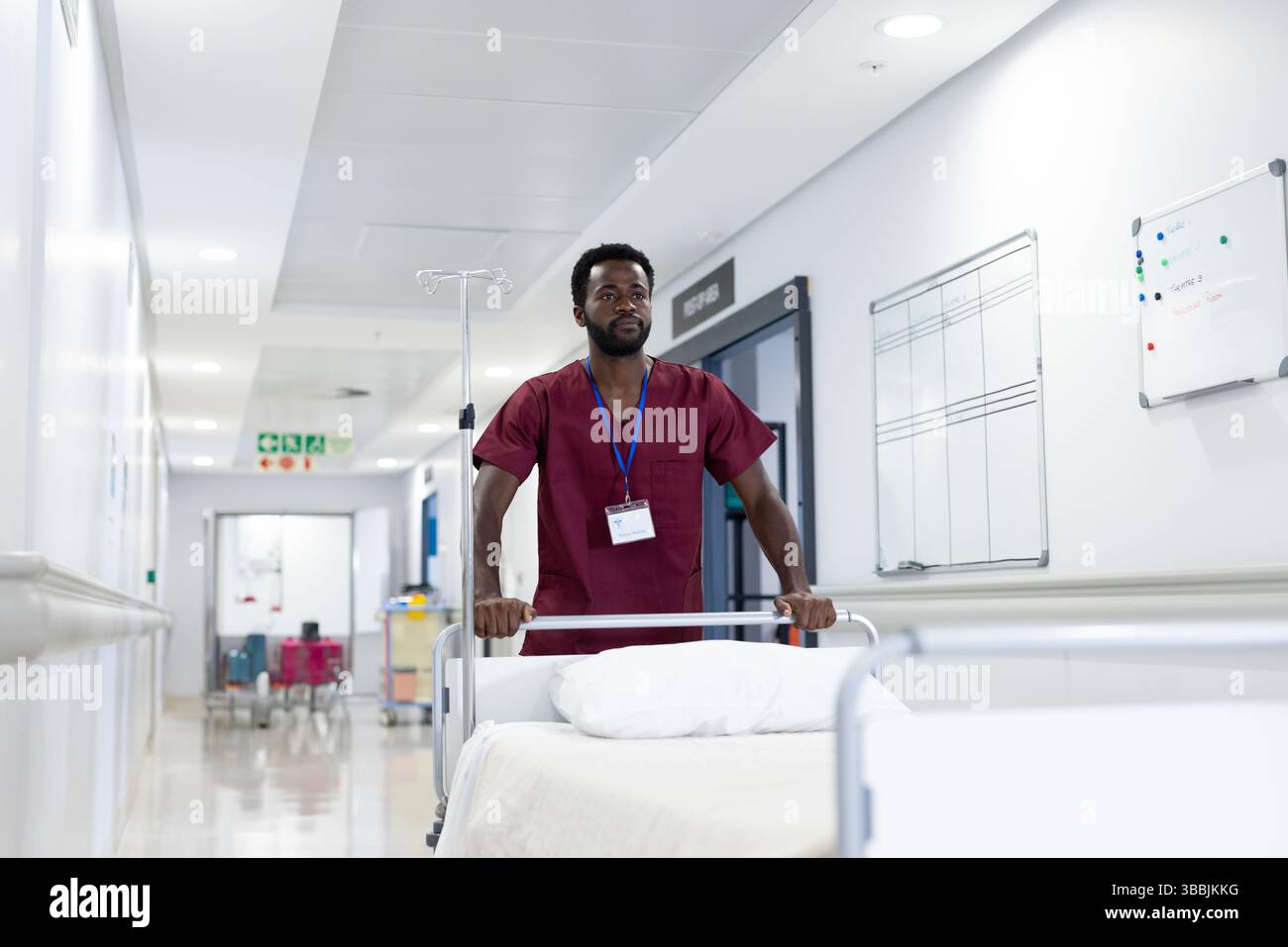 African American male hospital worker pushing bed in hospital corridor ...