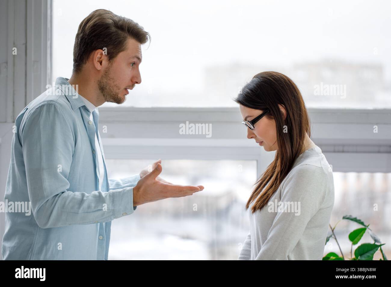 Sad couple having argument indoors, man expressing anger while woman ...