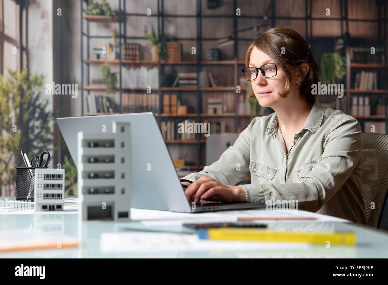 Female architect designer works on a project, laptop and blueprints on ...
