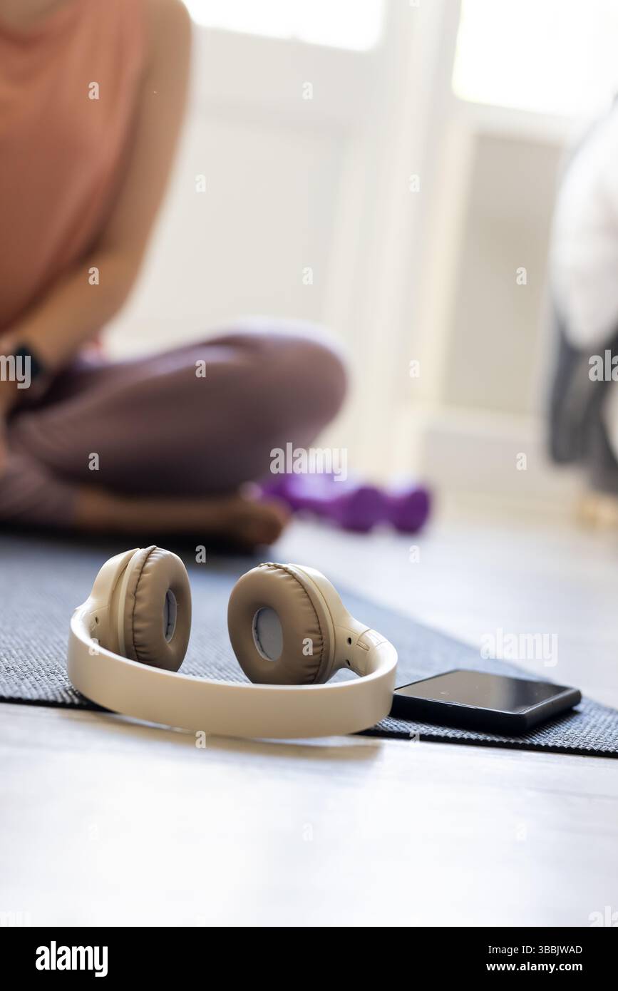 Asian woman in purple leggings sitting on yoga mat at home, with beige ...