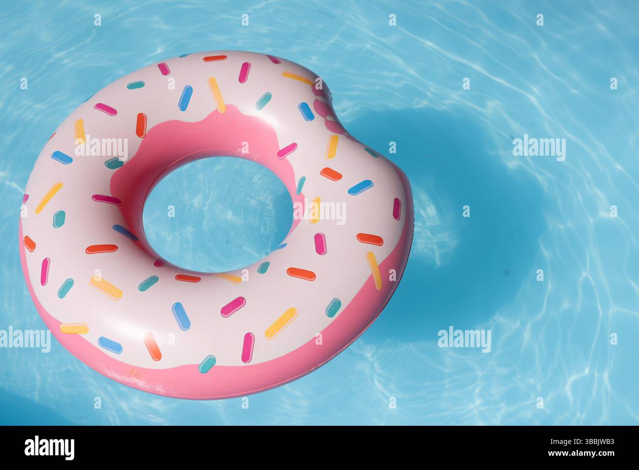 Doughnut-shaped inflatable swim ring floating on blue pool surface ...