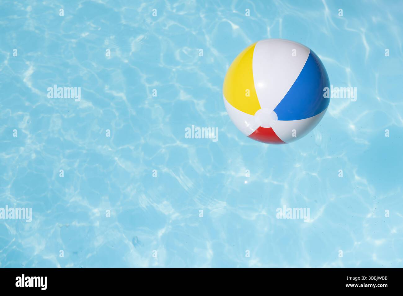 Inflatable beach ball floating on clear blue pool water, showing sunlit ...