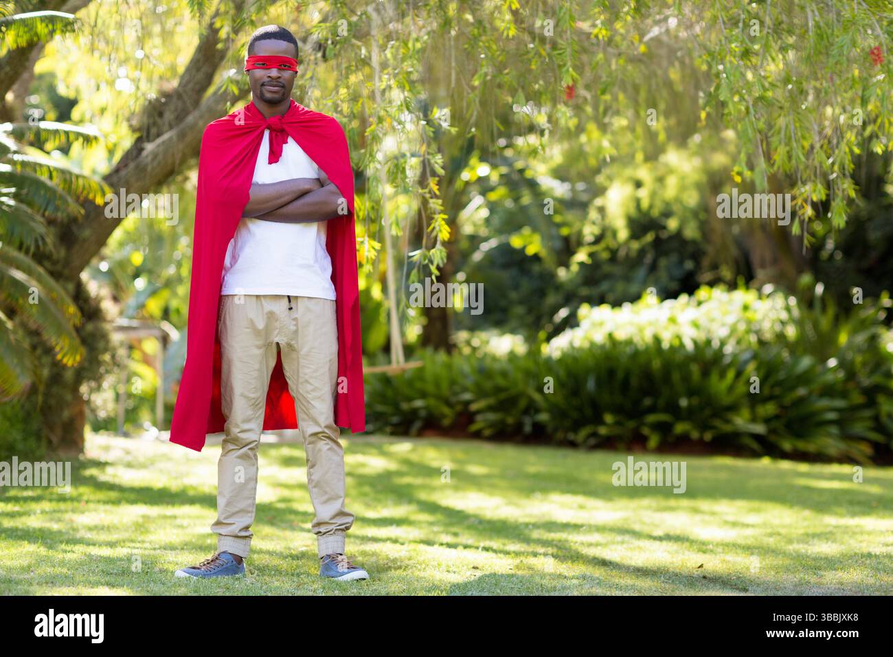 Standing African American man posing in sunlit backyard, with red ...