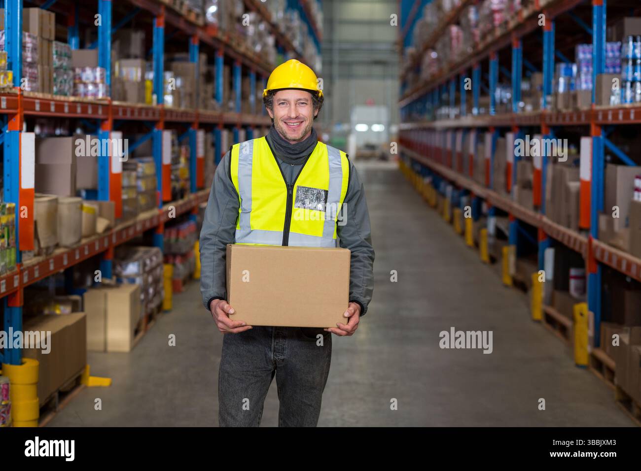 Standing man wearing safety vest, hard hat holding cardboard box in ...