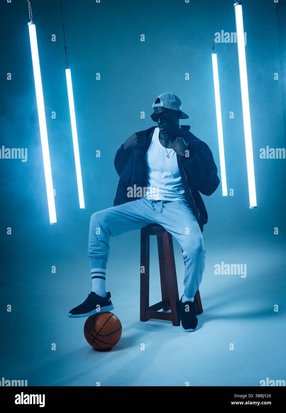 Adjusting African American man sitting on stool in blue haze studio ...