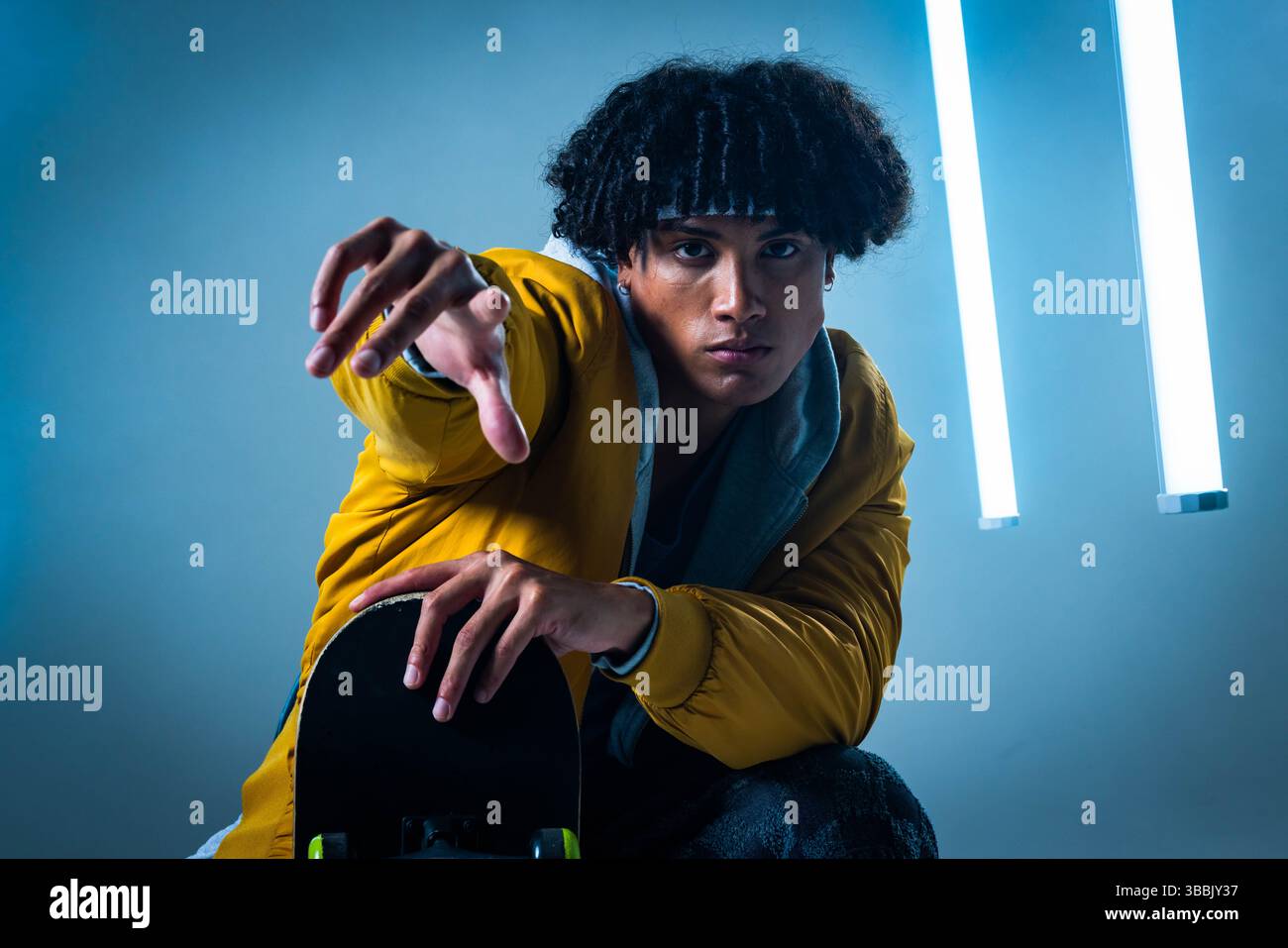 African American man in bomber jacket holding skateboard, reaching ...