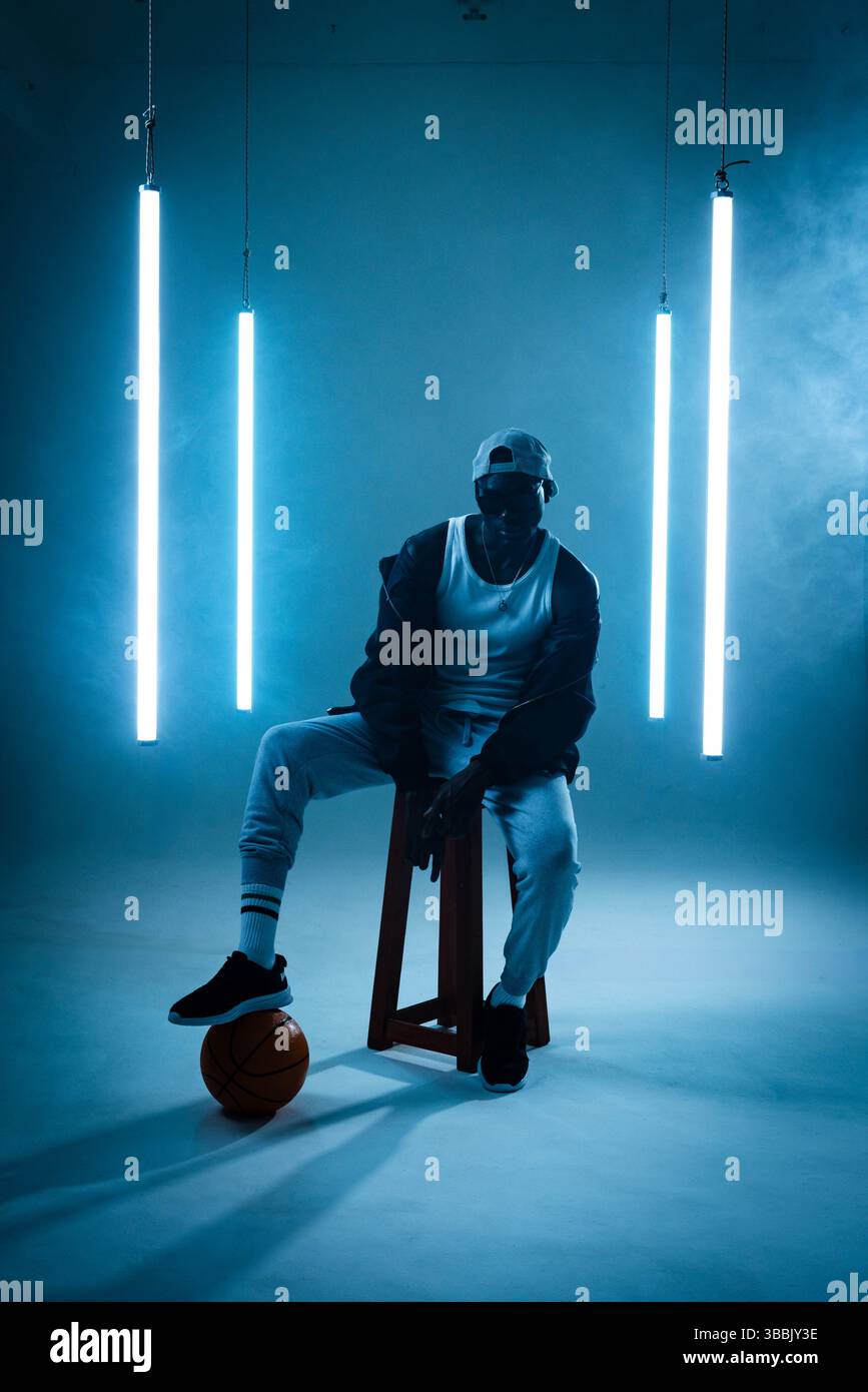 Sitting African American man wearing hoodie on stool in studio fog ...
