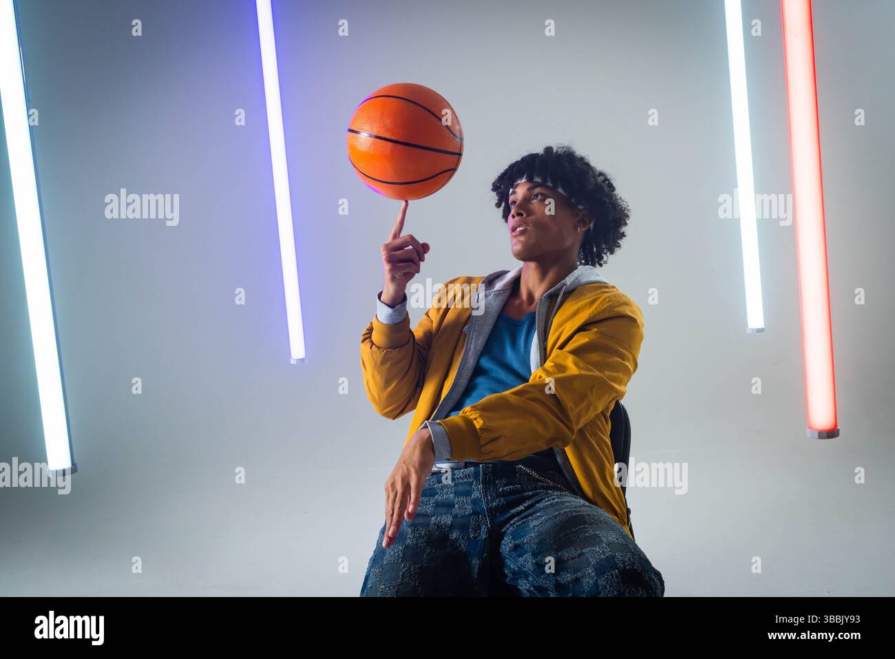 Spinning man wearing mustard jacket on black chair in studio, with ...
