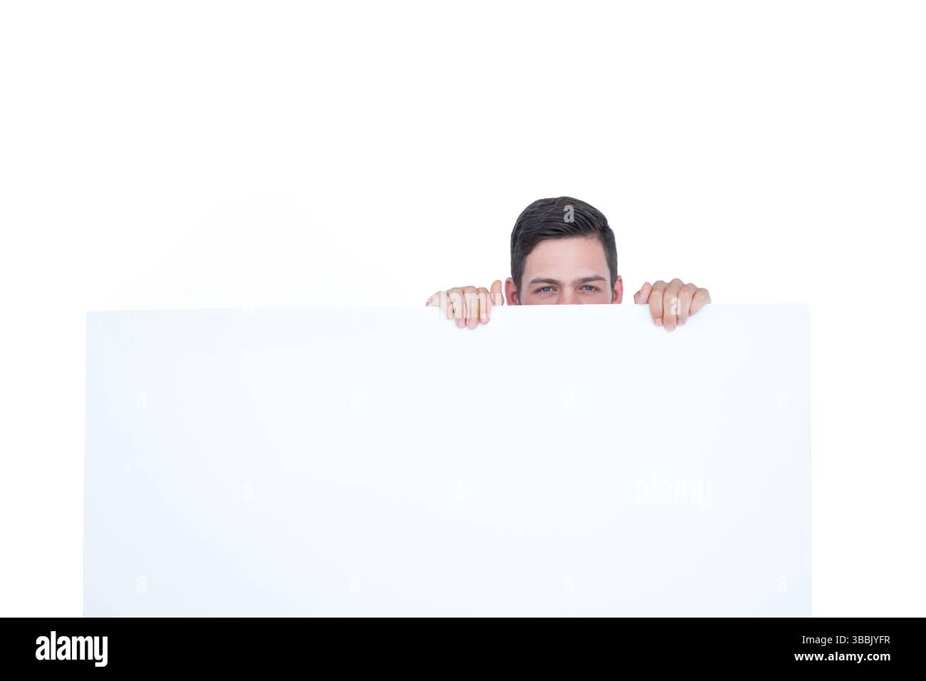 Peeking man gripping blank white poster board against seamless studio ...